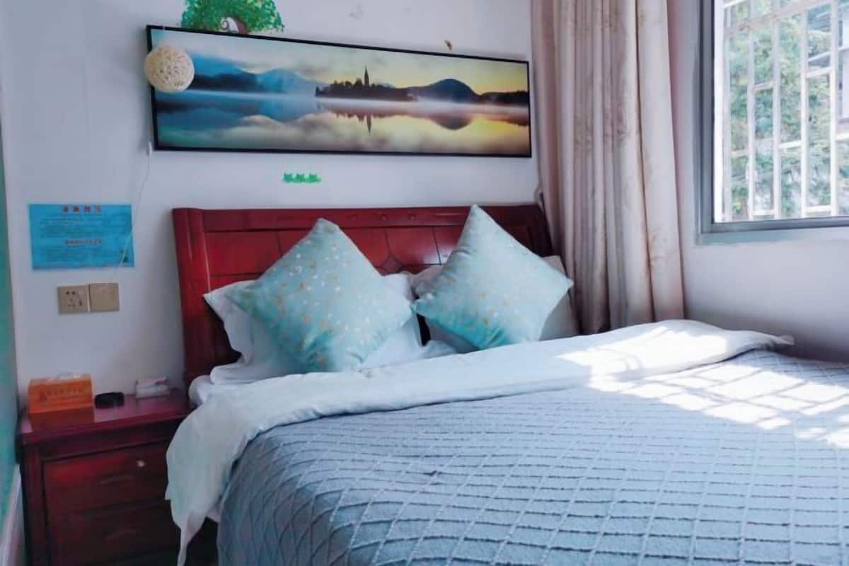 Uma cama bem arrumada com um edredom azul, uma cabeceira vermelha e duas almofadas azuis claras com padrão de bolinhas.