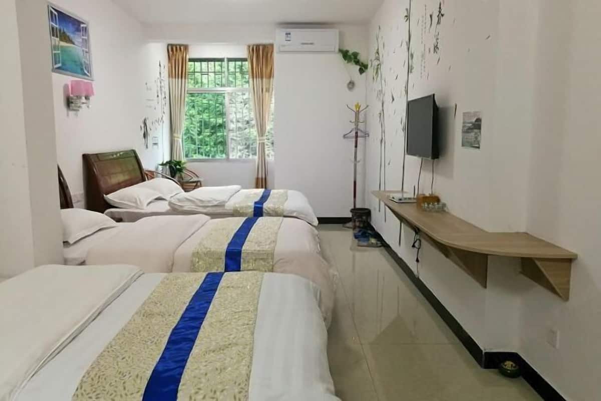 Quarto de hotel com duas camas, uma televisão, um cabideiro e uma janela com cortinas.