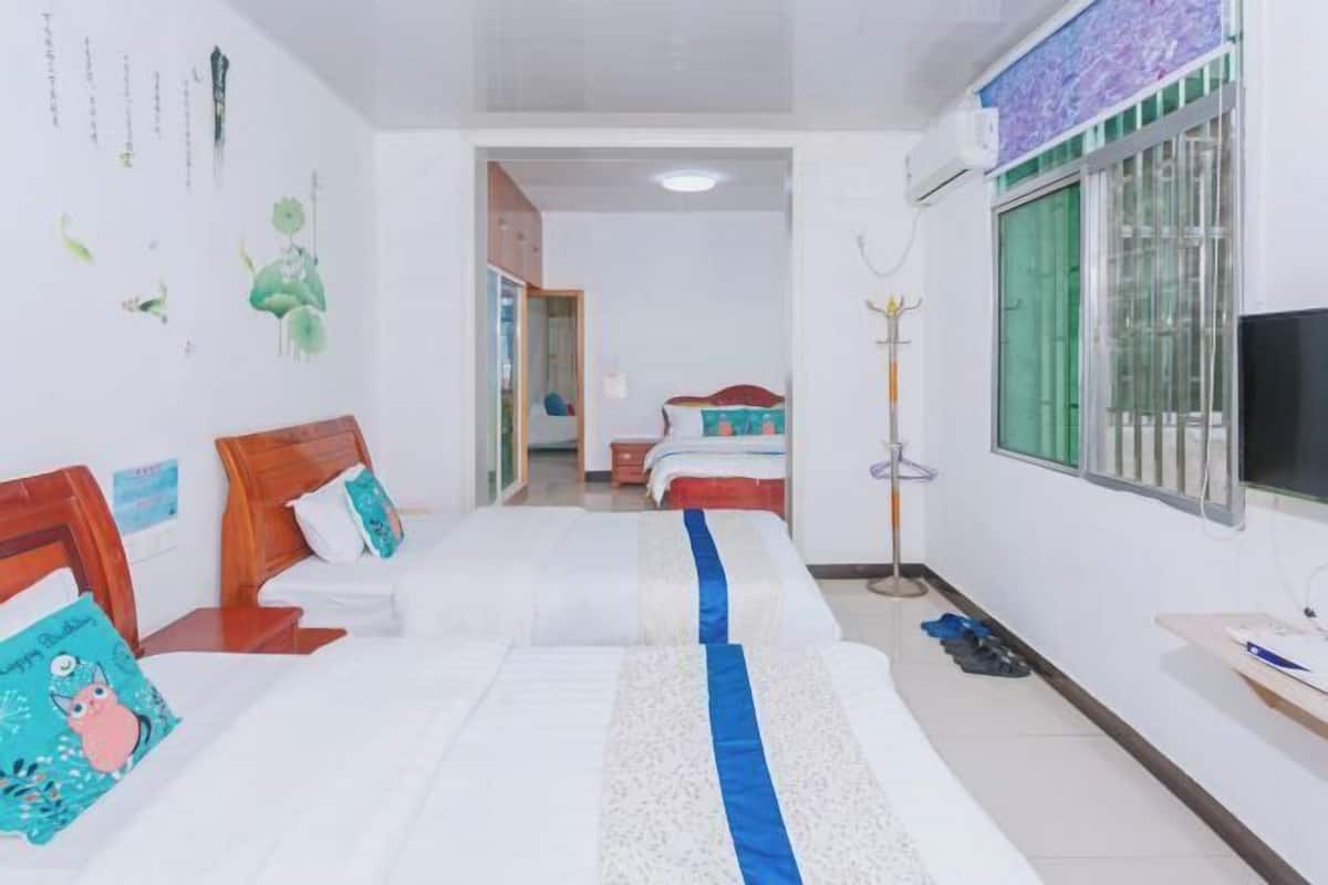 Quarto de hotel com duas camas, uma televisão, uma janela com grades e uma mesa de cabeceira com abajur.