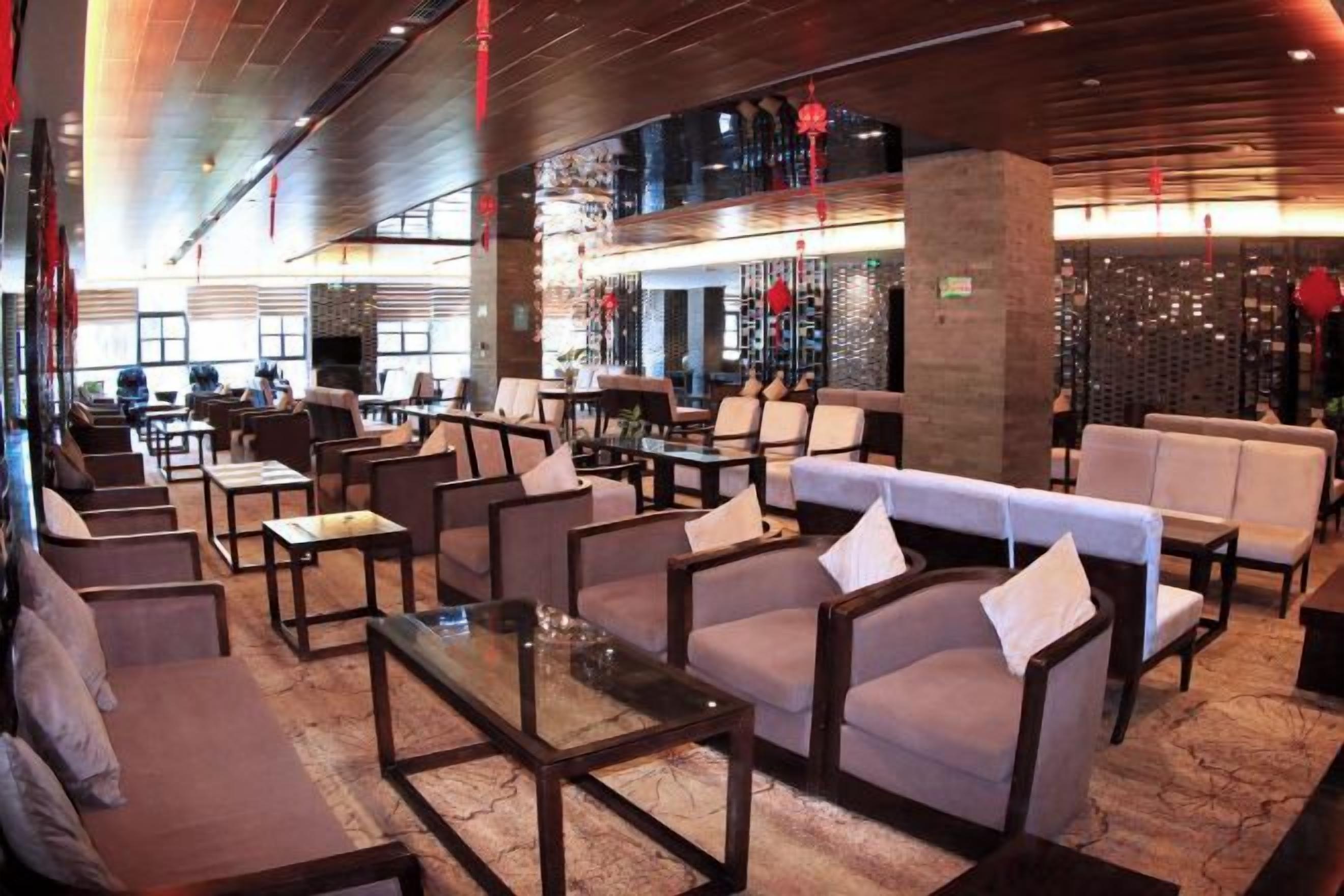 Um saguão de hotel com áreas de estar, um bar e uma parede decorativa.