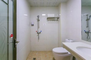 Uma casa de banho pequena e limpa, com sanita, lavatório e chuveiro.