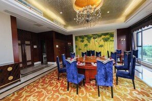 Sala de conferências com mesa redonda, cadeiras azuis e um candelabro.