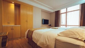Quarto de hotel com cama grande, armário de madeira, televisão de tela plana e janela com cortinas.
