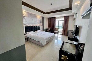 Quarto de hotel moderno com uma cama grande, uma escrivaninha, uma cadeira e uma televisão.