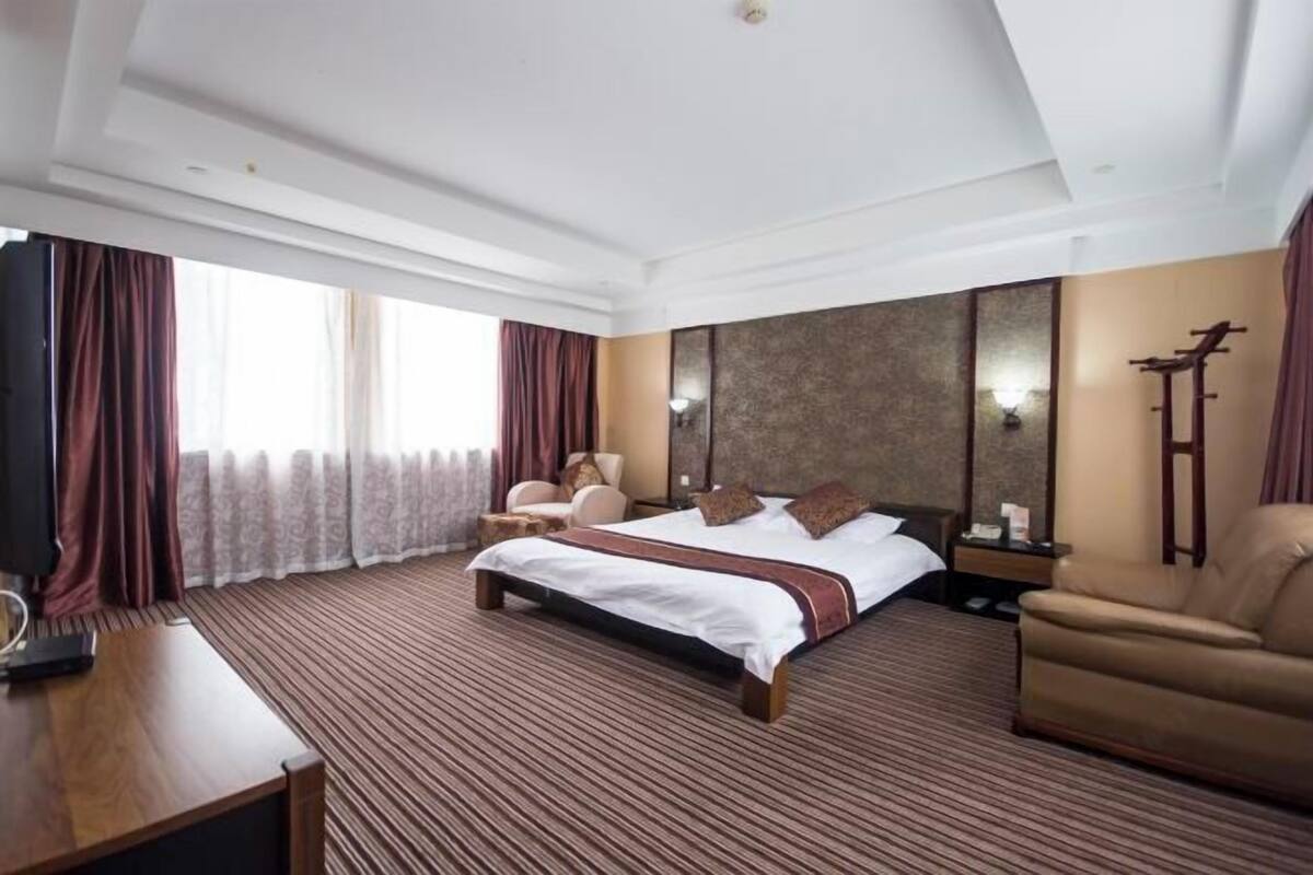 Quarto de hotel com uma cama grande, uma escrivaninha, uma cadeira e um sofá.