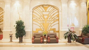 Um hall de entrada com balcão de recepção, dois sofás e plantas decorativas.