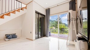 Um quarto espaçoso com escada, porta de vidro deslizante para uma varanda e uma grande TV de tela plana.