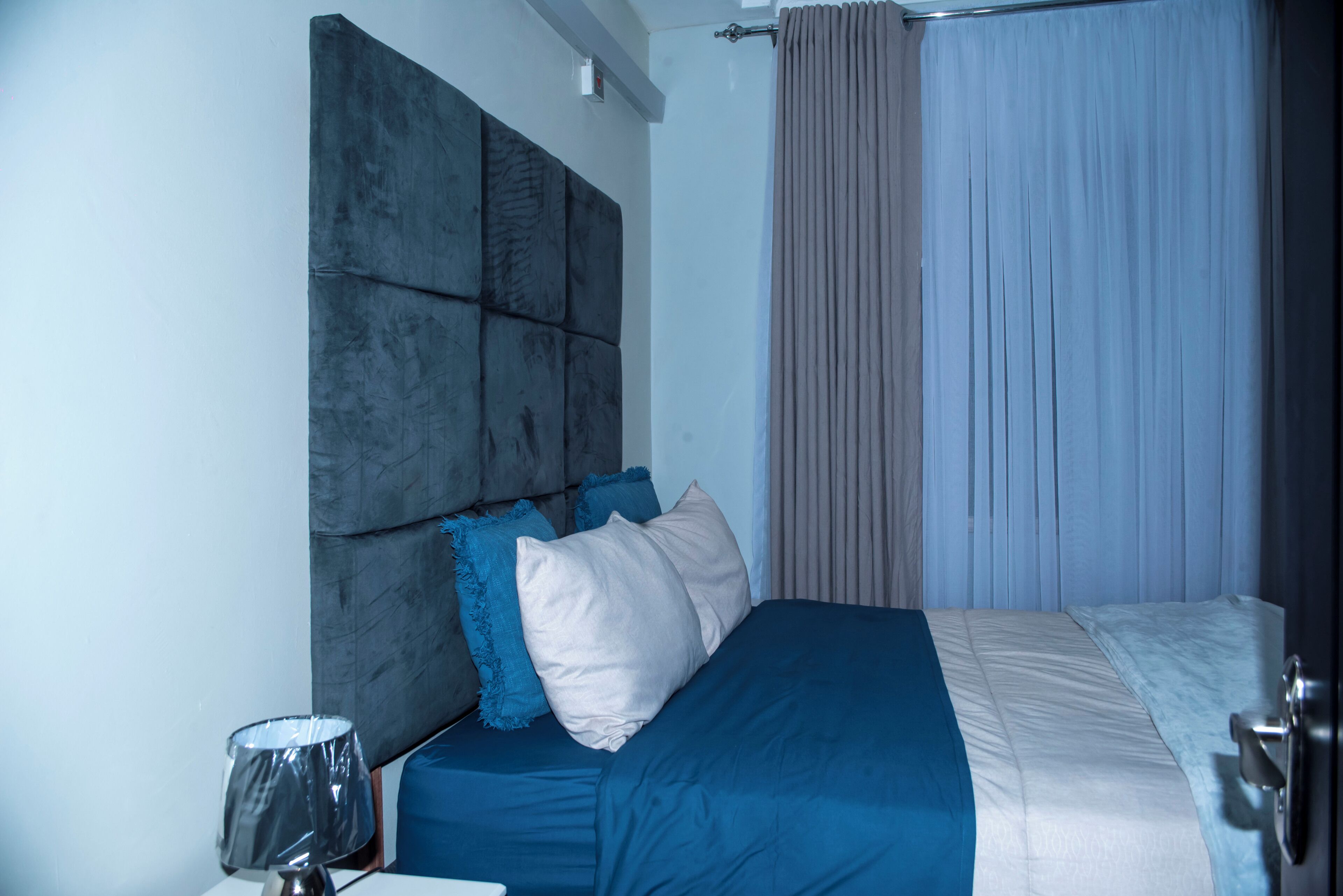 Quarto moderno com uma cama grande, cabeceira e cortina.