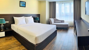 Quarto de hotel com uma cama grande, duas mesas de cabeceira com abajures, uma escrivaninha, uma cadeira e uma televisão.