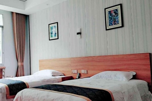 Quarto de hotel com duas camas, cabeceiras de madeira e obras de arte emolduradas nas paredes.