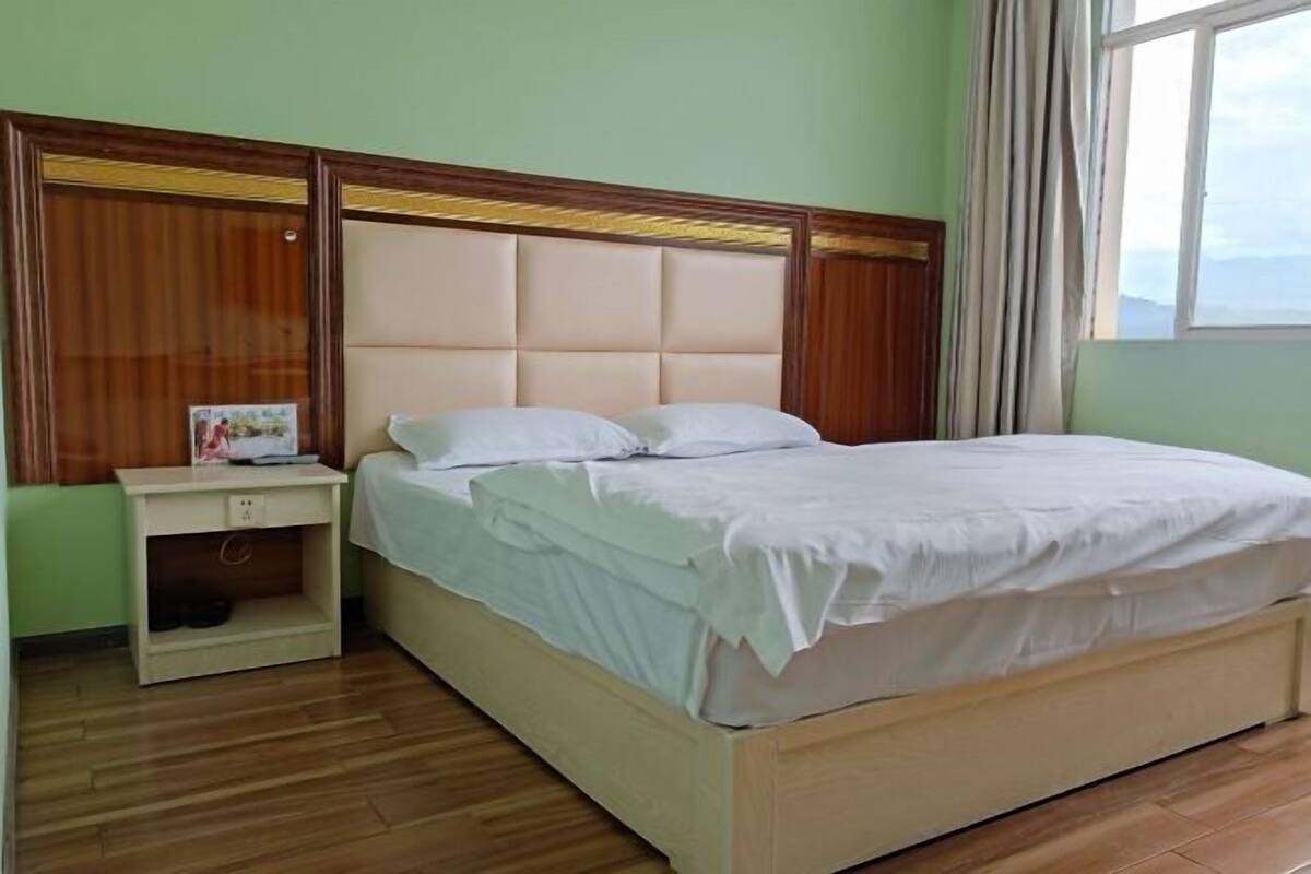 Um quarto com estrutura de cama de madeira, mesa de cabeceira com abajur e janela com cortinas.