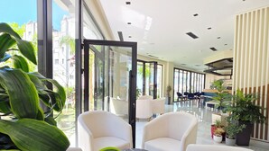 Um espaço moderno em ambientes internos, com grandes janelas, móveis brancos e plantas em vasos.