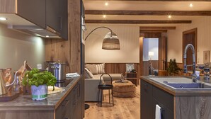 Cozinha moderna com armários de madeira, uma ilha central com pia e área de jantar com sofá e mesa.