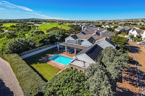 Um bairro residencial com casas modernas, piscina e gramado bem cuidado.