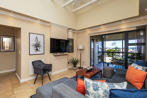Uma sala de estar moderna com televisão de tela plana, um sofá com almofadas estampadas, uma mesa de centro e uma planta em vaso.