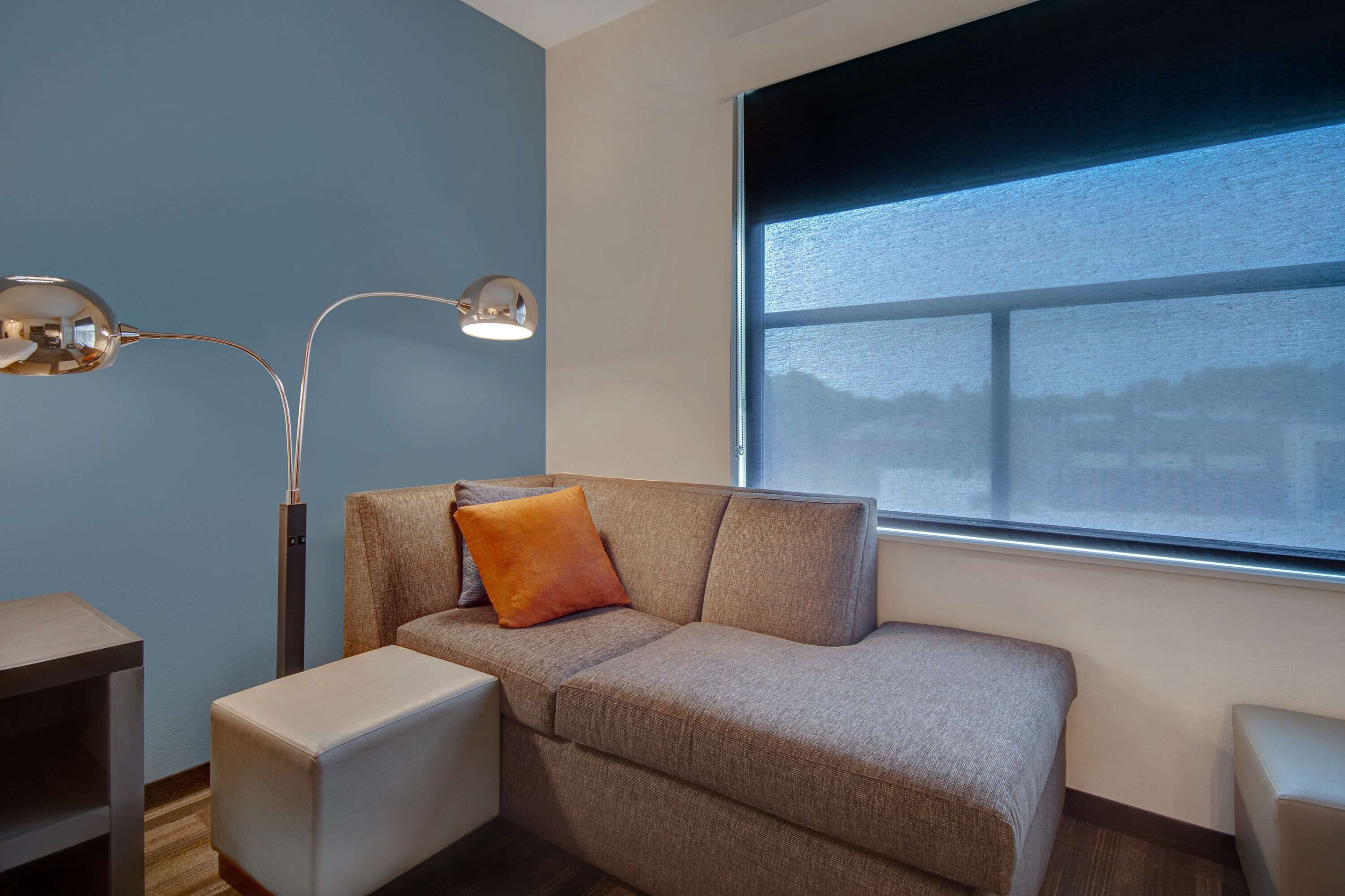 Quarto moderno com sofá, mesa lateral e abajur.