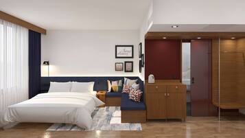 Quarto de hotel moderno com uma cama grande, um sofá-cama, um guarda-roupa de madeira, uma pequena cozinha e um banheiro com espelho e porta-toalhas.