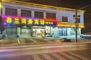 Um edifício com letreiro de neon, estacionamento e um poste de luz.