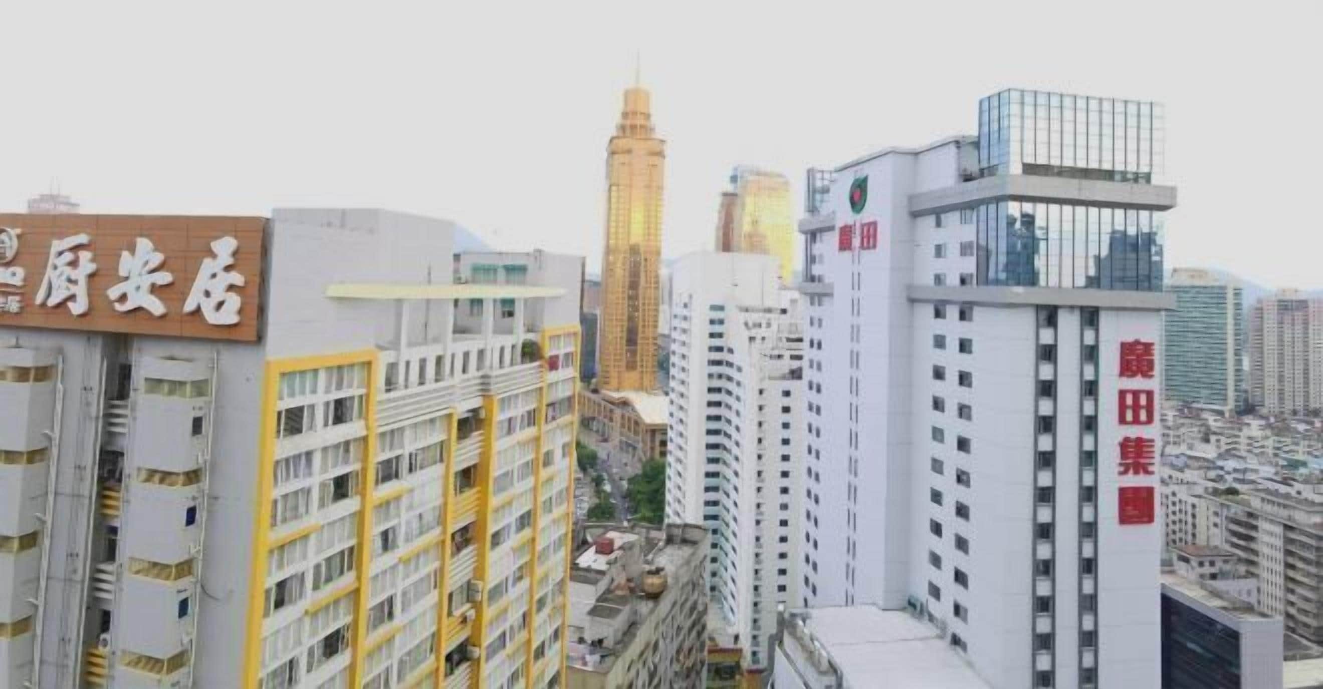 Um edifício alto com uma placa grande em idioma estrangeiro, cercado por outros edifícios imponentes em um ambiente urbano.