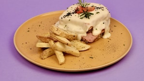 Um prato com sanduíche e batatas fritas sobre um fundo roxo.