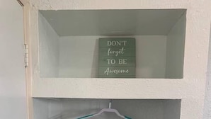 Um armário branco com uma placa motivacional que diz 'DON'T forget to be awesome' e um cabide de plástico pendurado no interior.