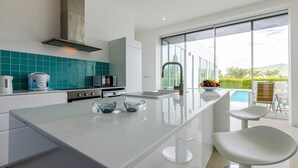 Uma cozinha moderna com uma bancada grande, forno embutido e vista para uma piscina.