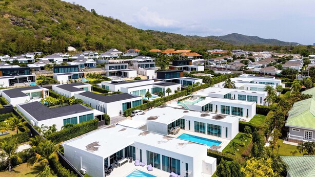 Um resort moderno com vários edifícios, cada um com grandes janelas e área de piscina.
