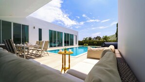 Uma área externa moderna com piscina, mesa de jantar e assentos confortáveis.