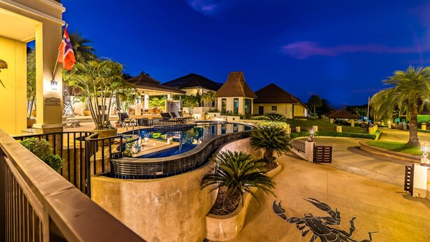Um resort com piscina, palmeiras e entrada bem iluminada.