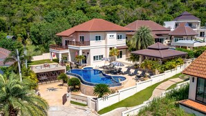 Bairro residencial com piscina, várias casas e vegetação exuberante.