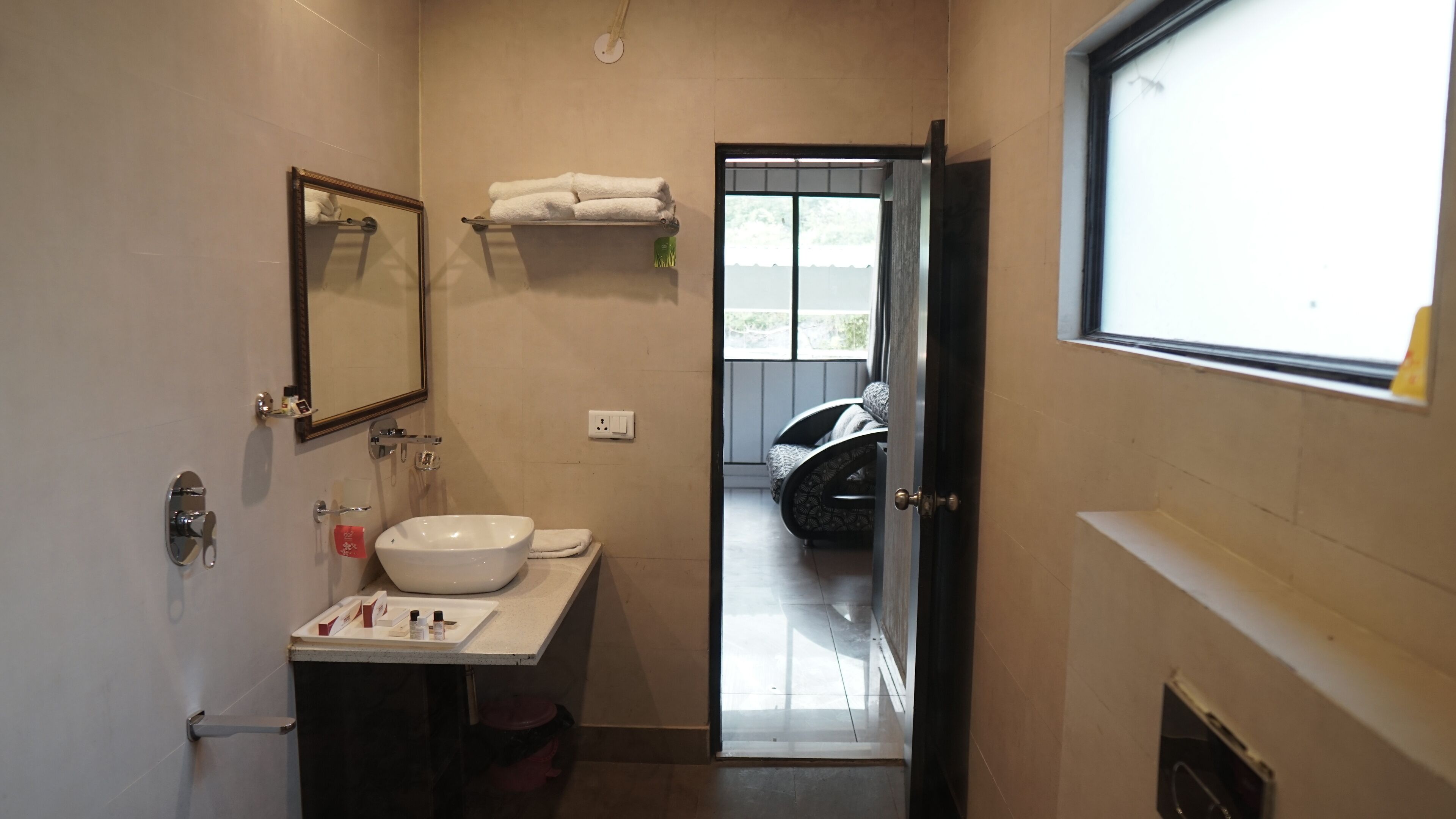 Casa de banho com lavatório, espelho, porta-toalhas e janela.
