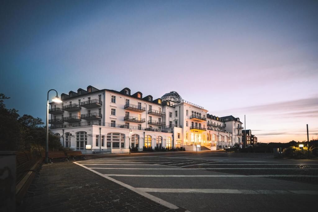 Um hotel com vários andares, varandas, uma estrutura em cúpula e uma entrada bem iluminada.