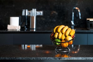 Uma bancada de cozinha com uma tigela de bananas e maçãs.
