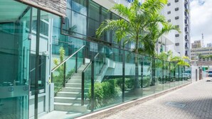 Um edifício moderno com paredes de vidro, uma escadaria e um caminho pavimentado.