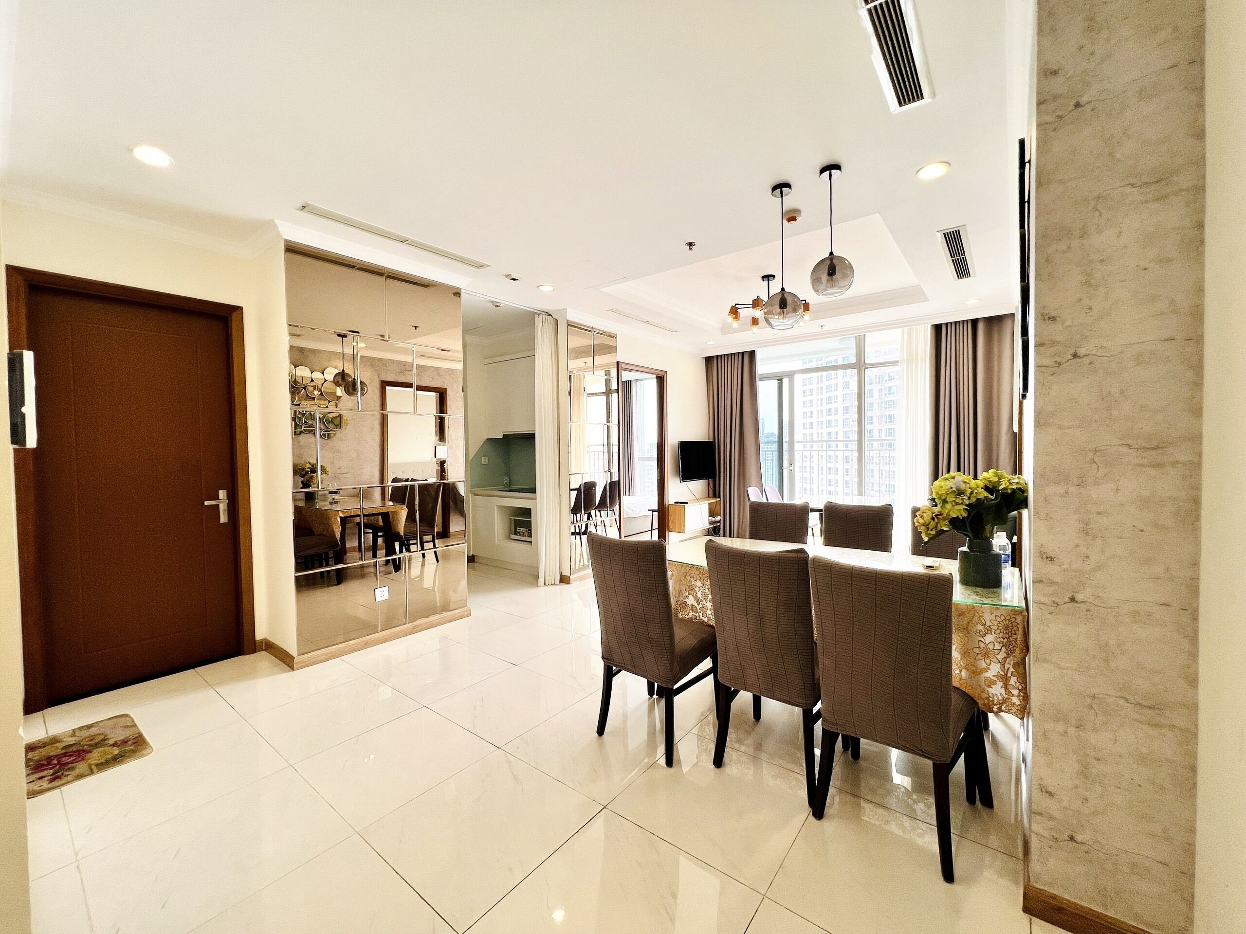 Quarto de hotel moderno com área de jantar, cozinha e uma grande janela com vista para a cidade.