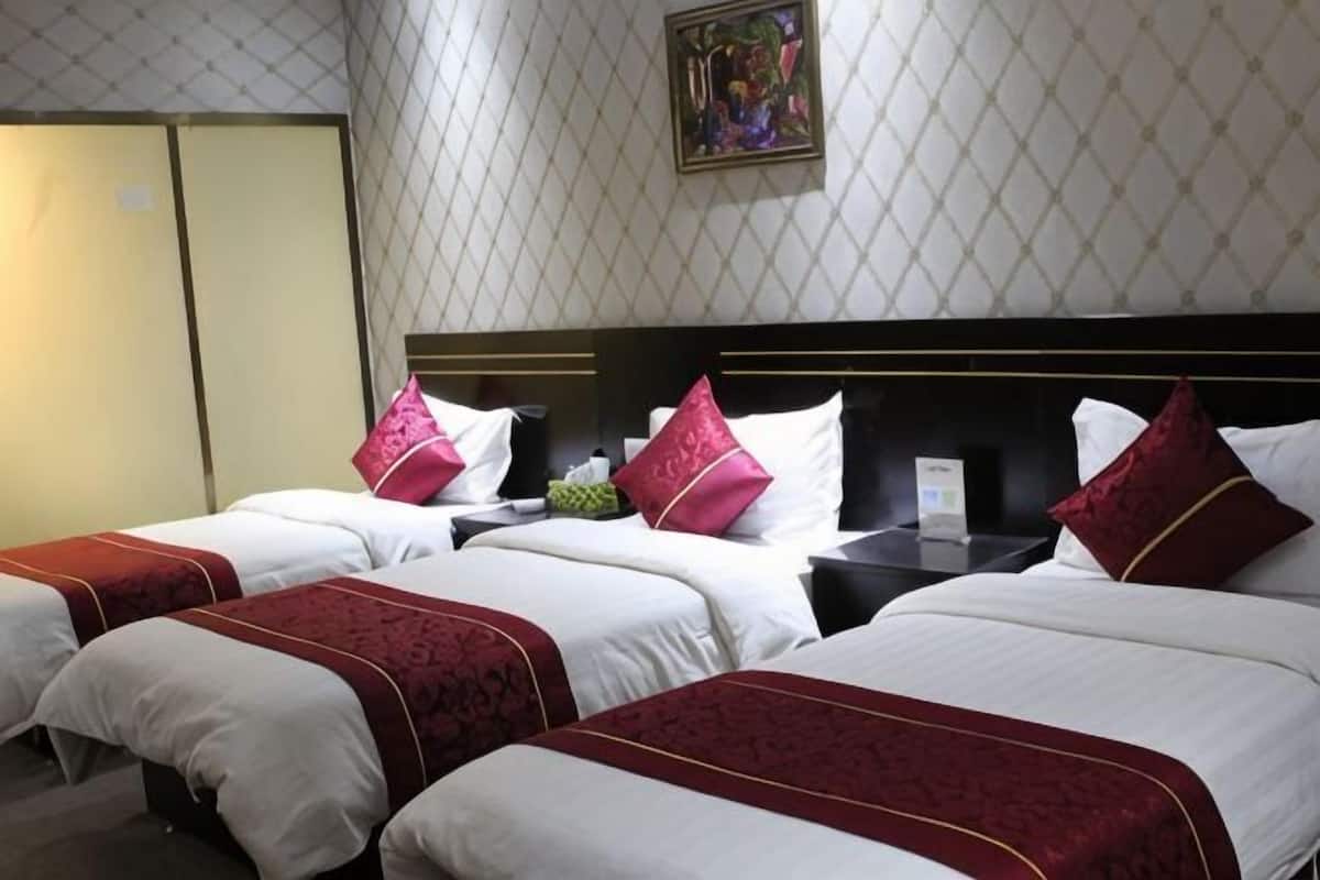 Quarto de hotel com duas camas, mesa de cabeceira, guarda-roupa e um quadro na parede.