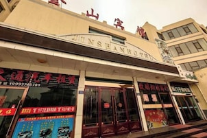 Um edifício com a placa 'JINSHAN HOTEL' e uma entrada visível com portas de vidro.