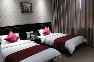 Quarto de hotel com duas camas, uma mesa de cabeceira, um quadro na parede e uma janela com cortinas.