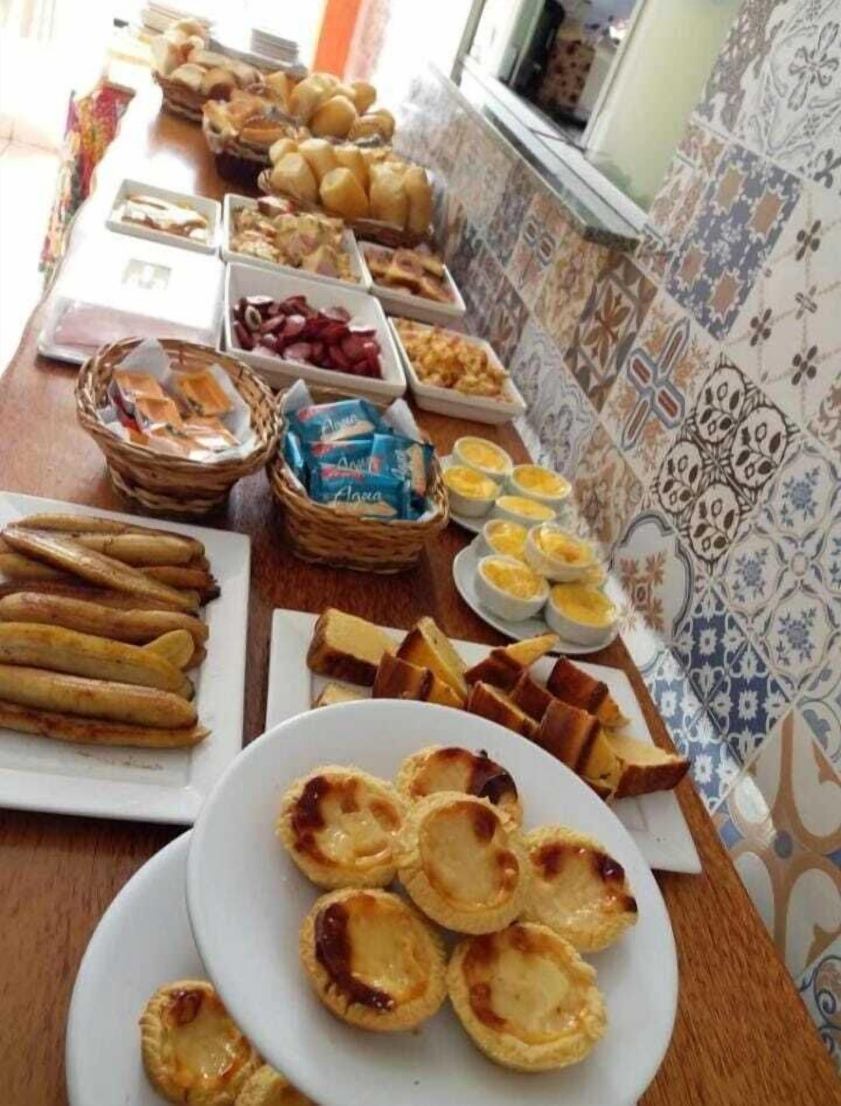 Uma mesa de buffet com diversos alimentos, incluindo pão, doces e patês.
