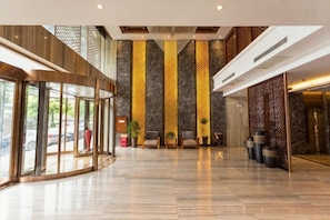 Um hall amplo com piso de mármore, balcão de recepção e entrada de vidro.