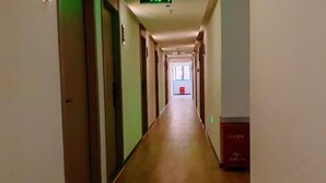 Um corredor longo e estreito com soalho de madeira e portas em ambos os lados.