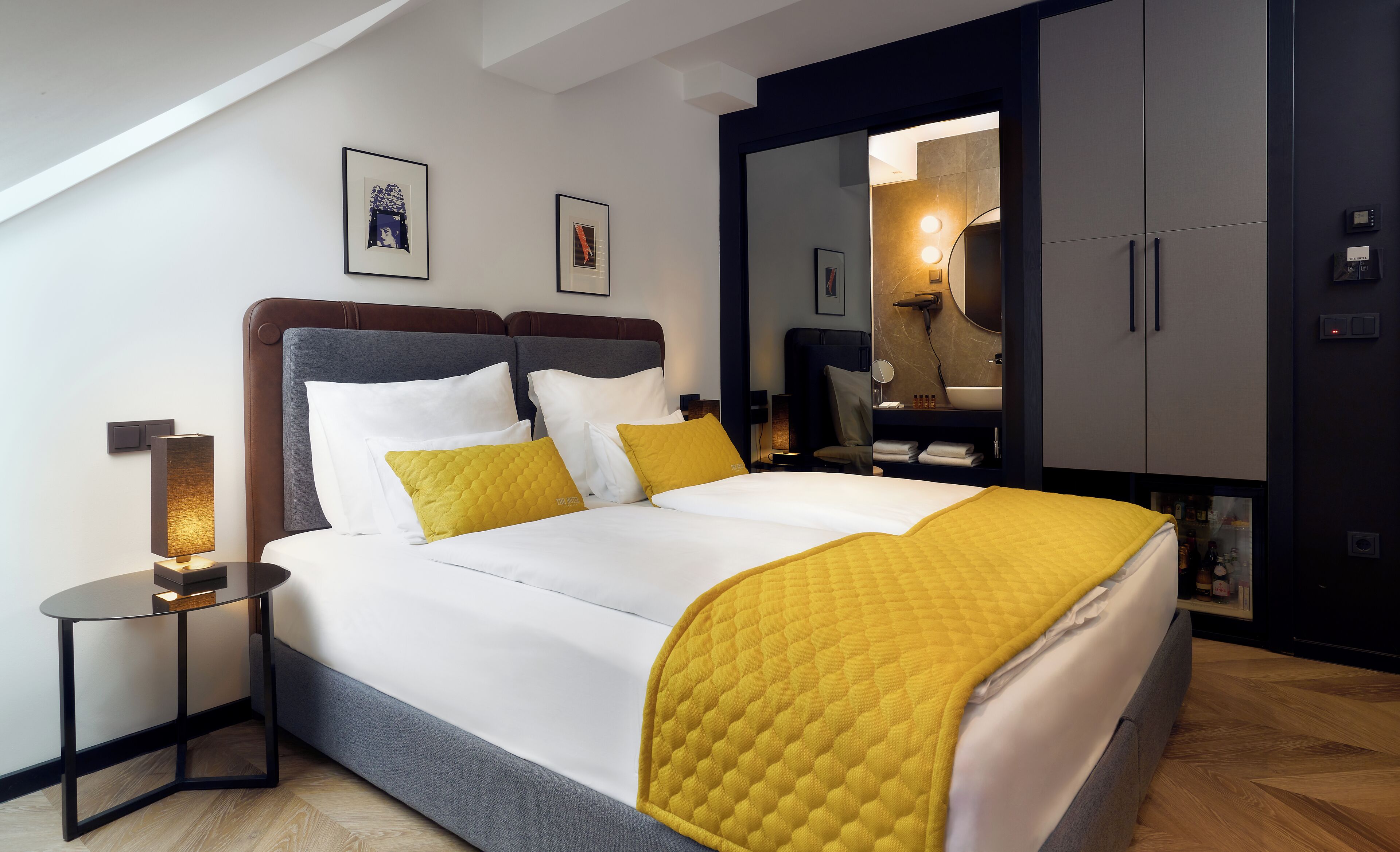 Quarto moderno com cama grande, mesas de cabeceira, espelho e guarda-roupa.