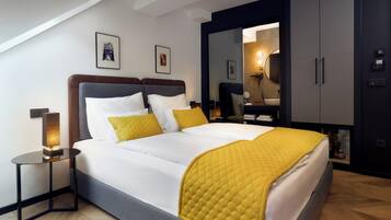 Quarto moderno com cama grande, mesas de cabeceira, espelho e guarda-roupa.