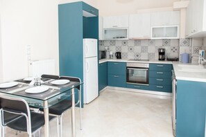 Cozinha moderna com armários verde-água, mesa de jantar de vidro e eletrodomésticos de aço inoxidável.