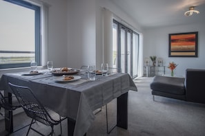 Uma área de jantar com uma mesa posta para dois, um banco e vista para o exterior.