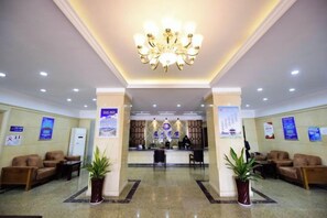 Um saguão de hotel com balcão de recepção, área de estar e um candelabro.