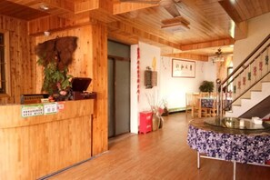 Uma área de recepção com balcão de madeira, escadas e uma sala de jantar com mesa e cadeiras.