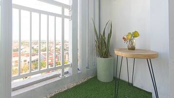 Varanda com vista para a cidade, um vaso de planta e uma pequena mesa com um vaso.