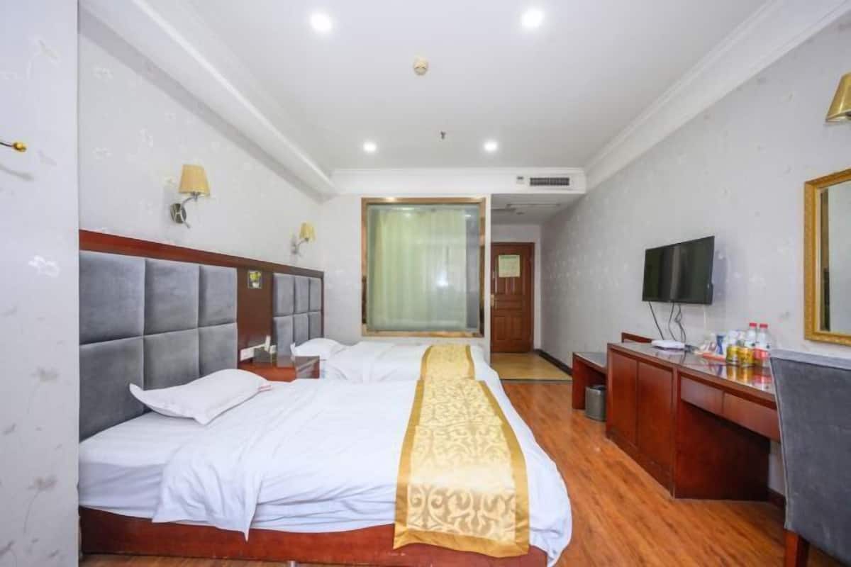 Quarto de hotel com uma cama grande, uma escrivaninha, uma televisão e um espelho.