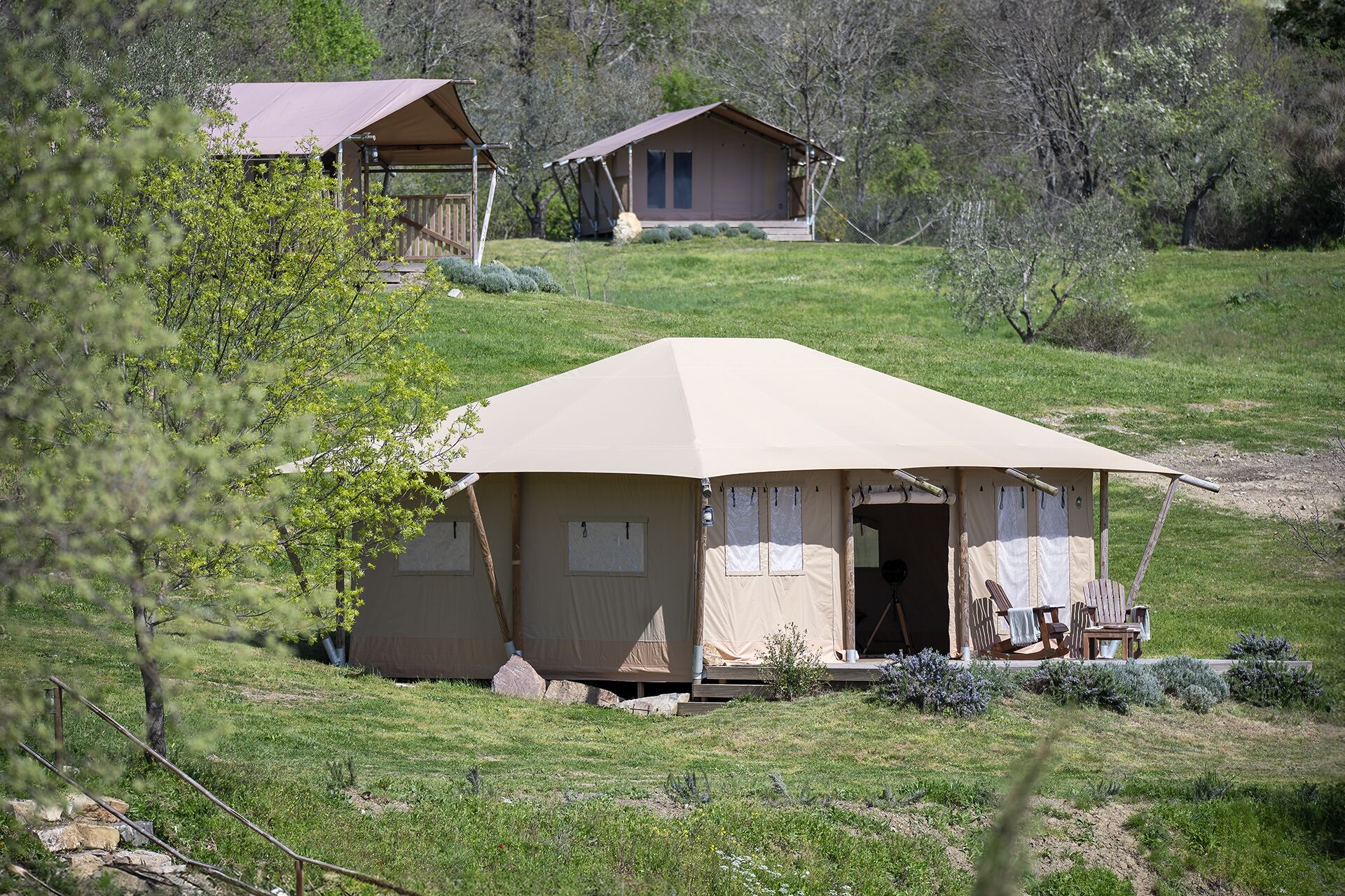 Acomodação em tenda com varanda, área de estar externa e vista da paisagem ao redor.